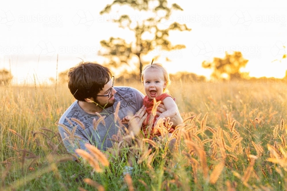 Image of Happy smiling baby in farm paddock with dad at sunset ...