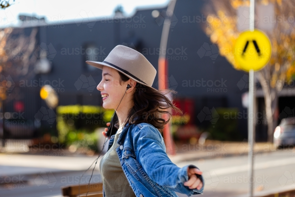 Image of Happy teenager listening to music on phone dancing in urban ...