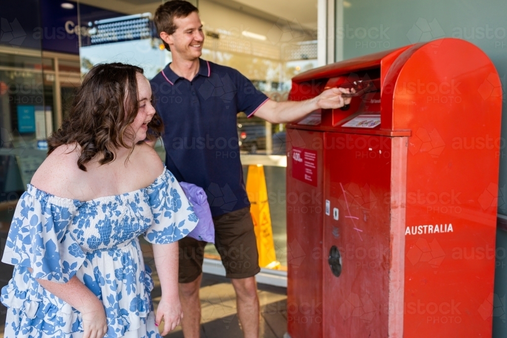 Image of Happy teenager with down syndrome using post office box to ...