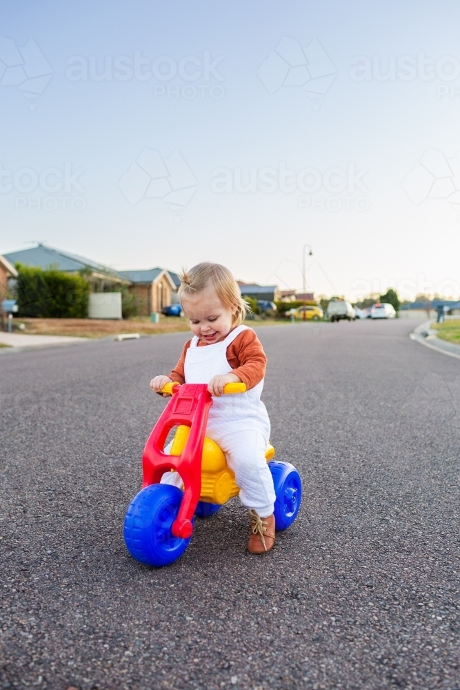 Image of Happy toddler child riding on dune buggy trike on quiet urban ...