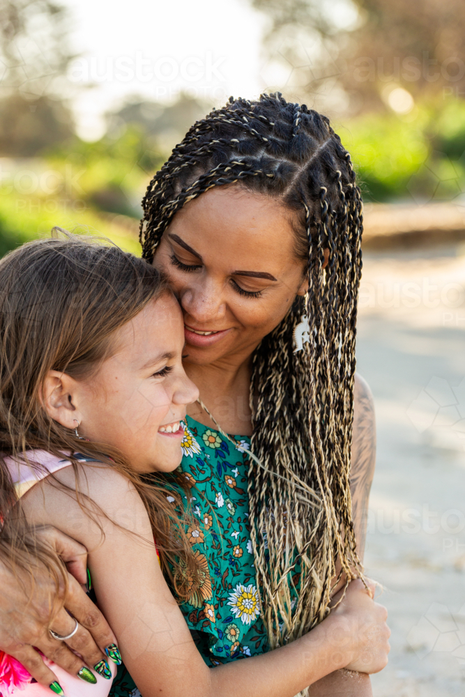 Image of Happy Torres Strait Islander woman with young nine year old daughter sitting together ...