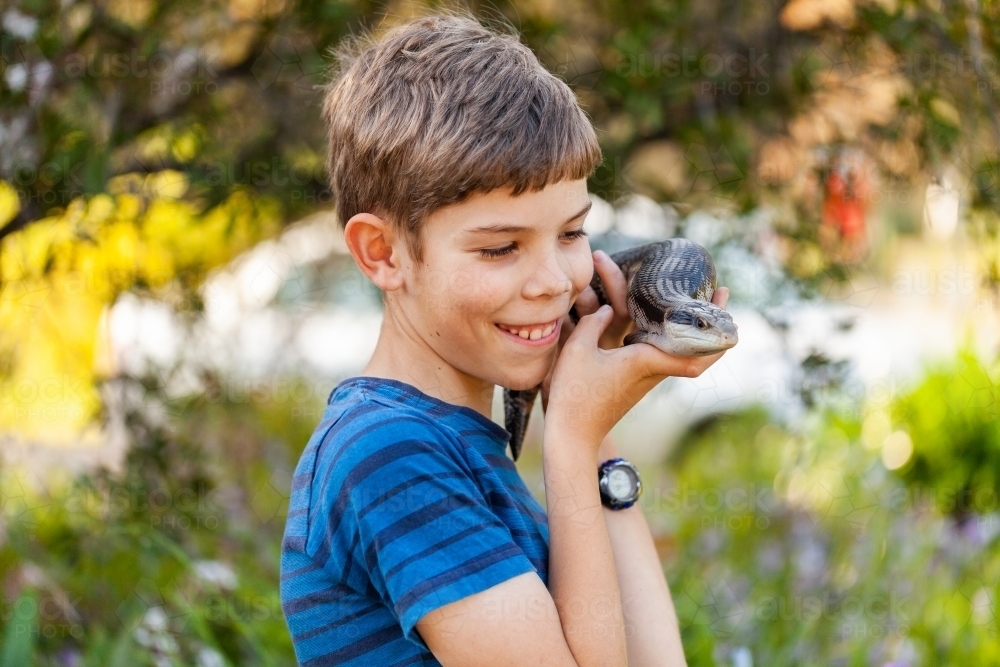 Image of Happy tween boy with blue-tongued lizard outside in garden ...