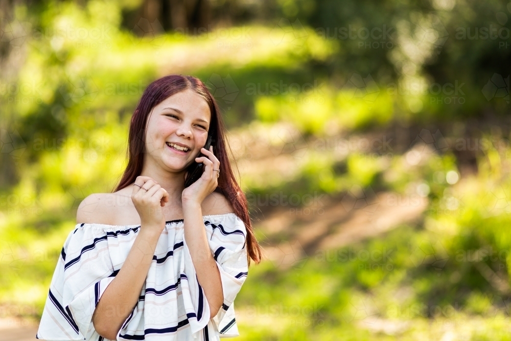 Image of Happy tween girl using her mobile phone outside for a phone ...