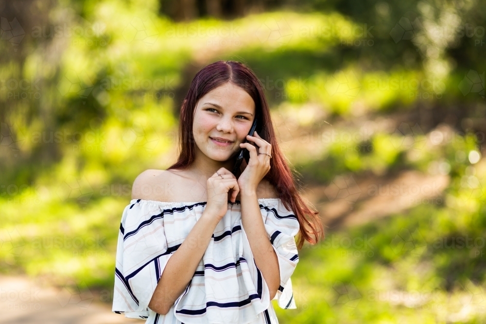 Image of Happy tween girl using her mobile phone outside for a phone ...