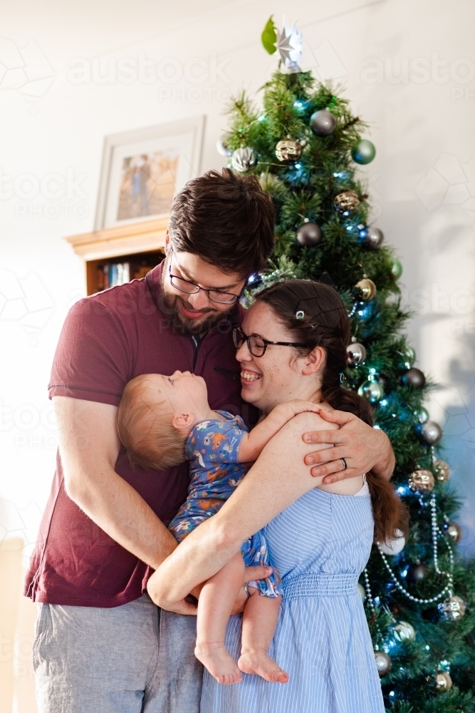 Image of Happy young australian family of three hug beside Christmas ...
