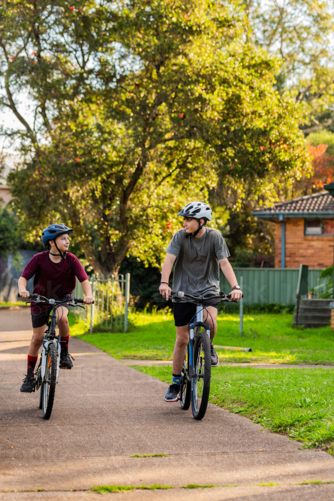 Image of Happy young Australian kids riding their bikes together on ...