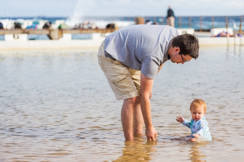 Image of Happy young baby girl sitting in shallow sea water in ocean ...