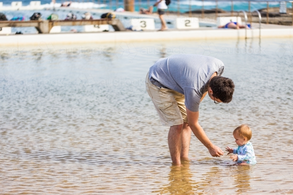 Image of Happy young baby girl sitting in shallow sea water in ocean ...