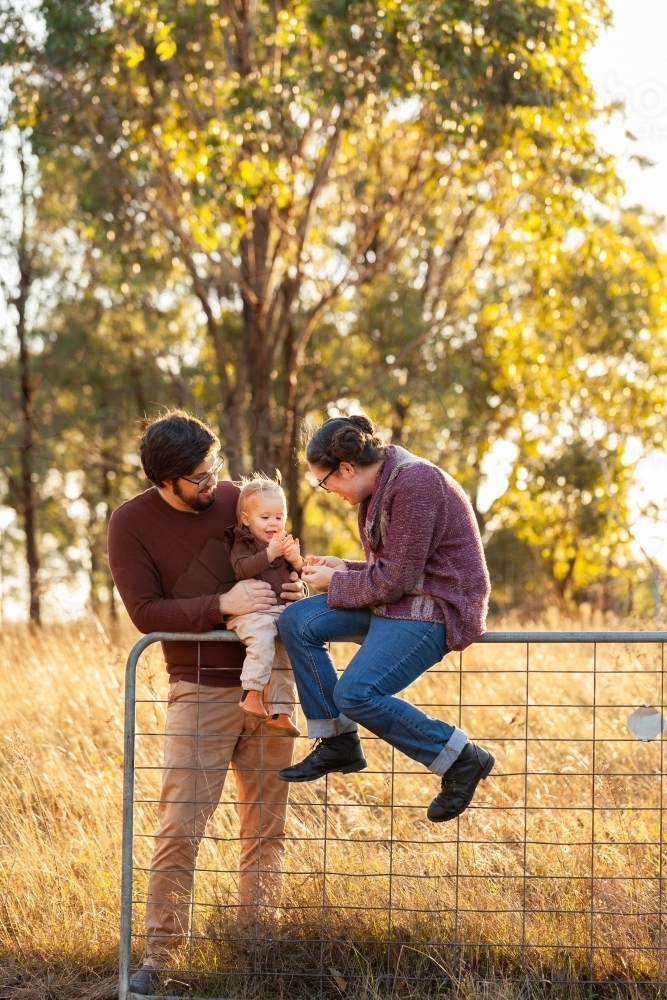 Image of Happy young family in country setting together on farm gate in ...