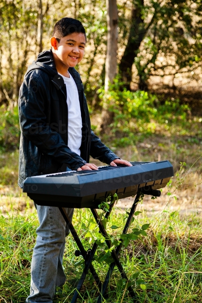 Image of Happy young Filipino boy playing keyboard outside - Austockphoto