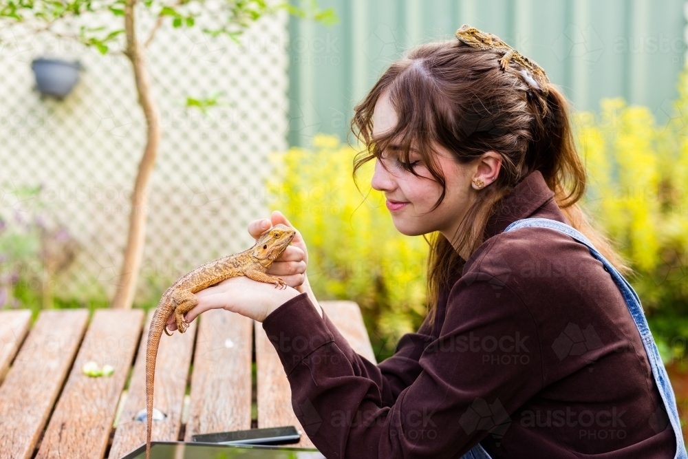 Image of Happy young woman sitting at picnic bench in garden with pet ...