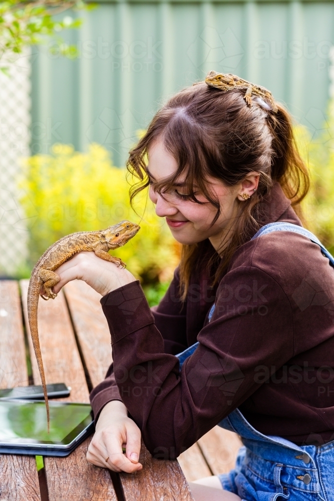 Image of Happy young woman sitting at picnic bench in garden with pet ...