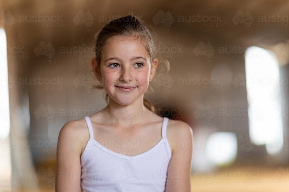 Image of head and shoulders of child wearing white singlet in big farm ...