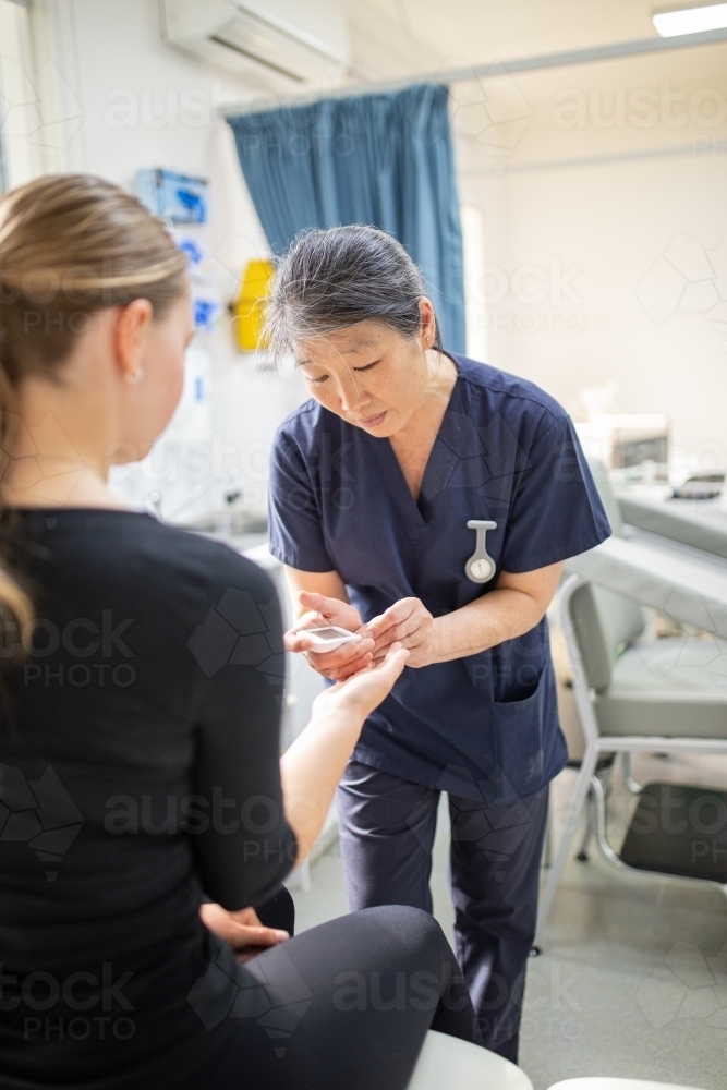 Image of Health worker getting a blood sample from a woman using a ...