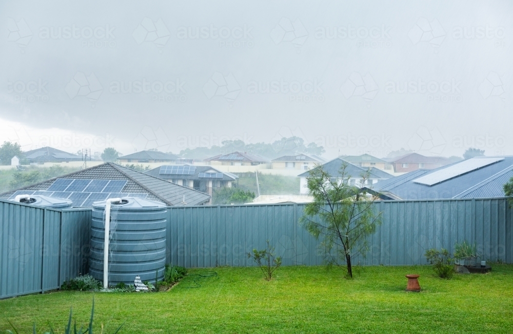 Image of Heavy rainfall in backyard with water overflowing from tank ...