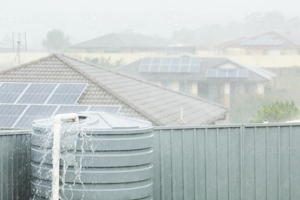 Image of Heavy rainfall in backyard with water overflowing from tank ...