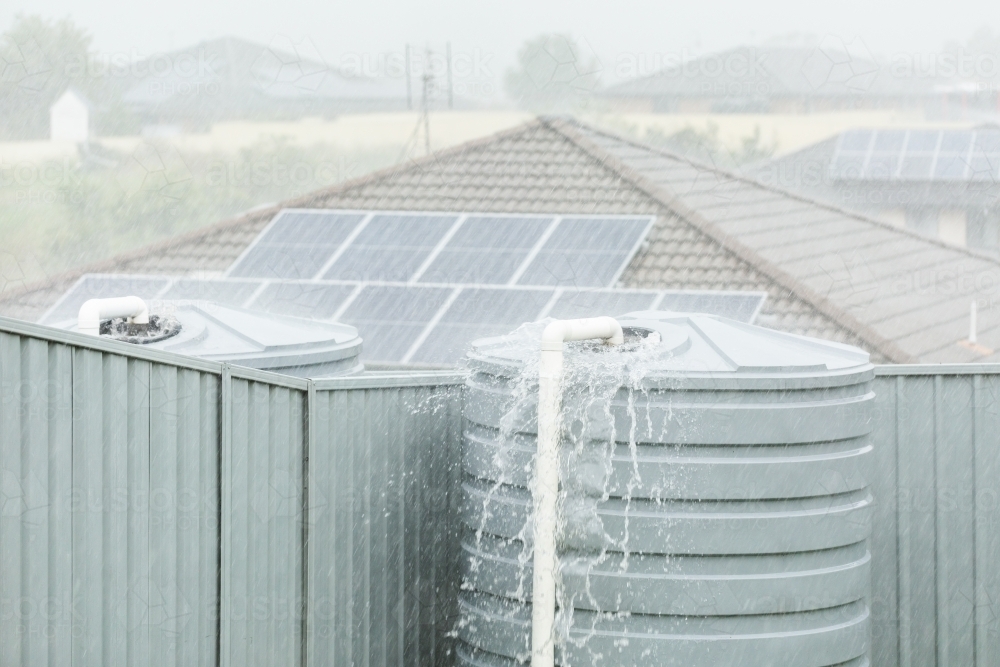 Image of Heavy rainfall in backyard with water overflowing from tank ...