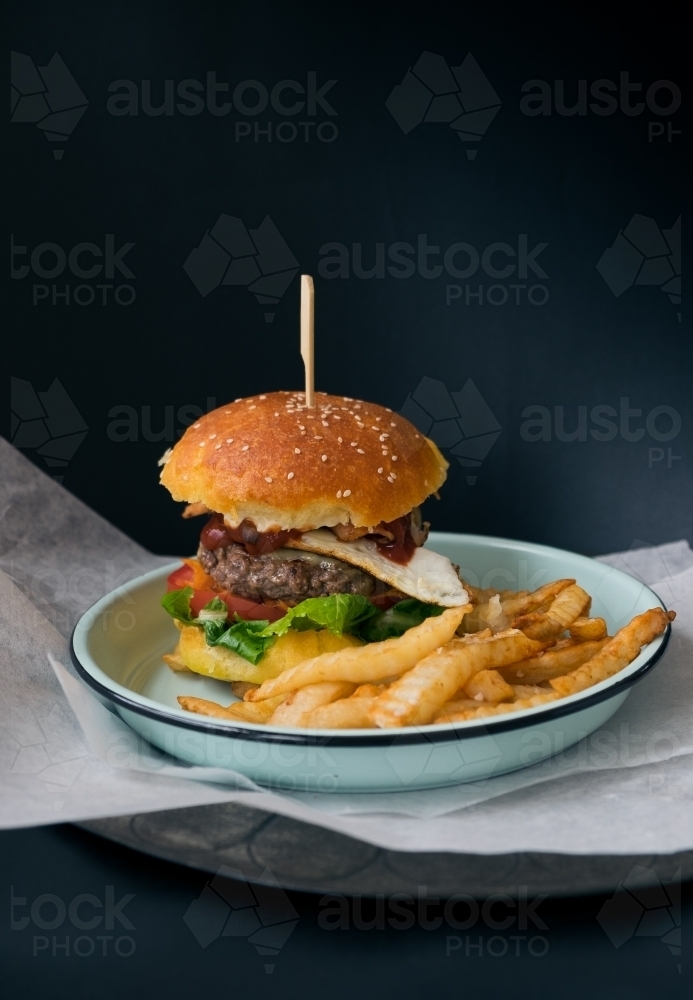 Image of Home made beef burger and oven chips on a plate - Austockphoto