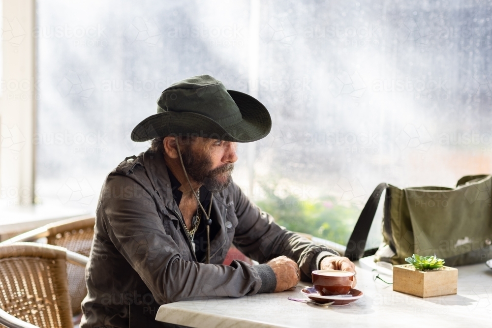 Image of Homeless man having a cup of coffee at a cafe - Austockphoto