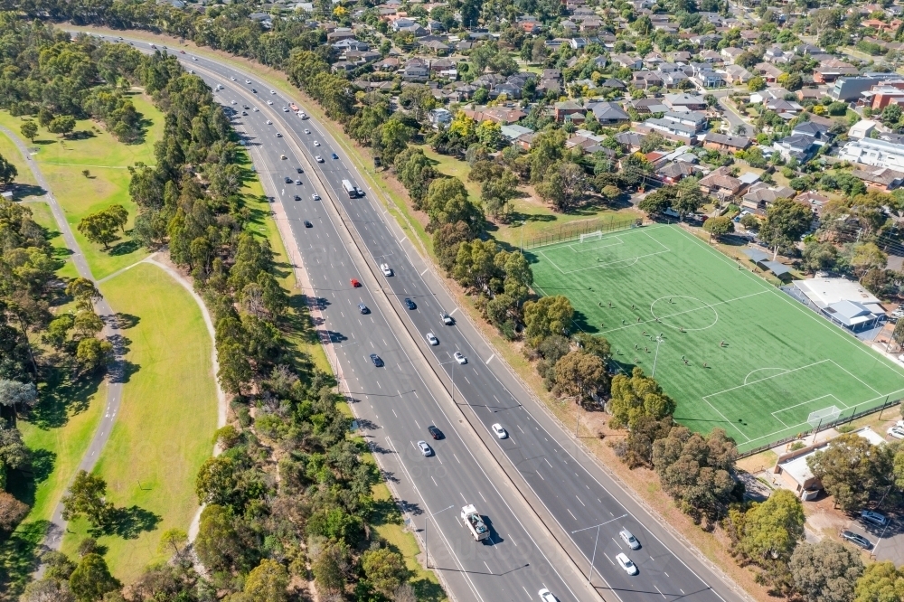 Image of Horizontal aerial view of long, busy freeway with parkland on ...