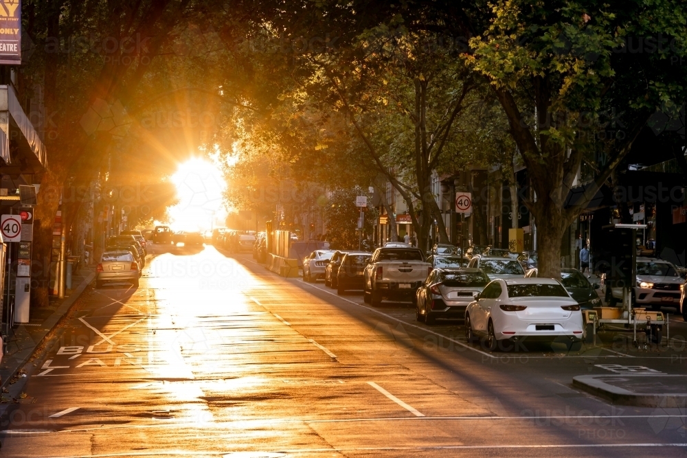 Image of Horizontal shot of a city street with cars parked and sunshine ...