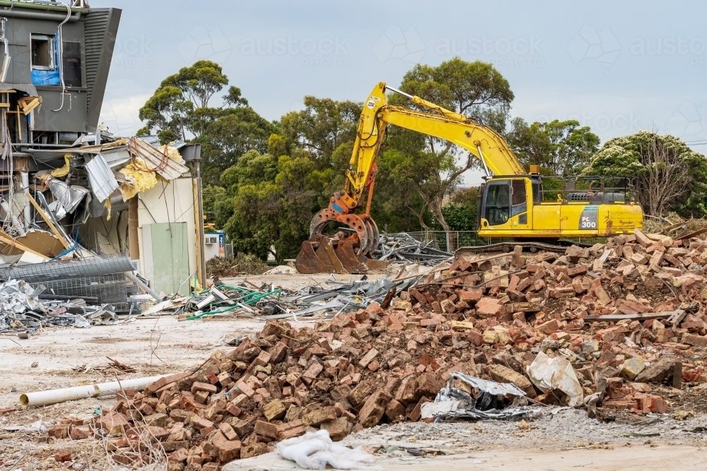 Image of Horizontal shot of a yellow backhoe on a demolition site with ...
