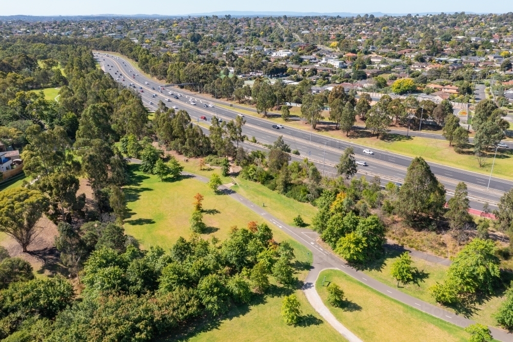 Image of Horizontal aerial view of long, busy freeway with parkland on ...