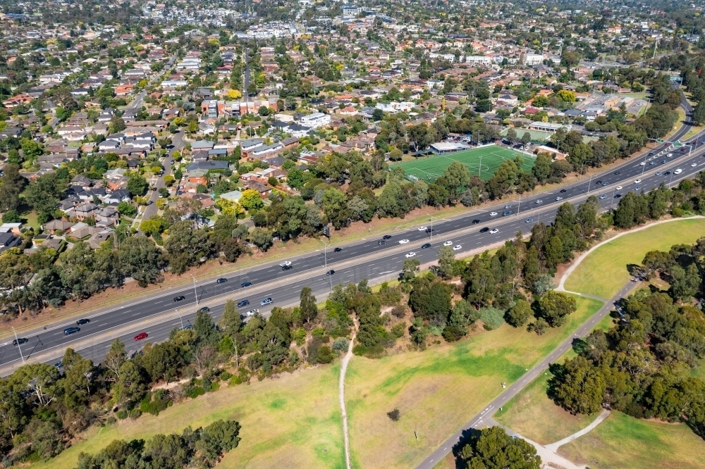 Image of Aerial view of long, busy freeway with parkland on one side ...