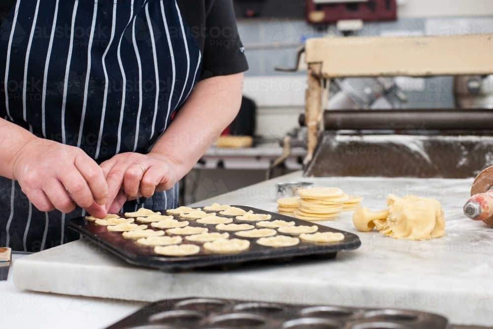 Image of Hhospitality worker working pastry into a tray - Austockphoto