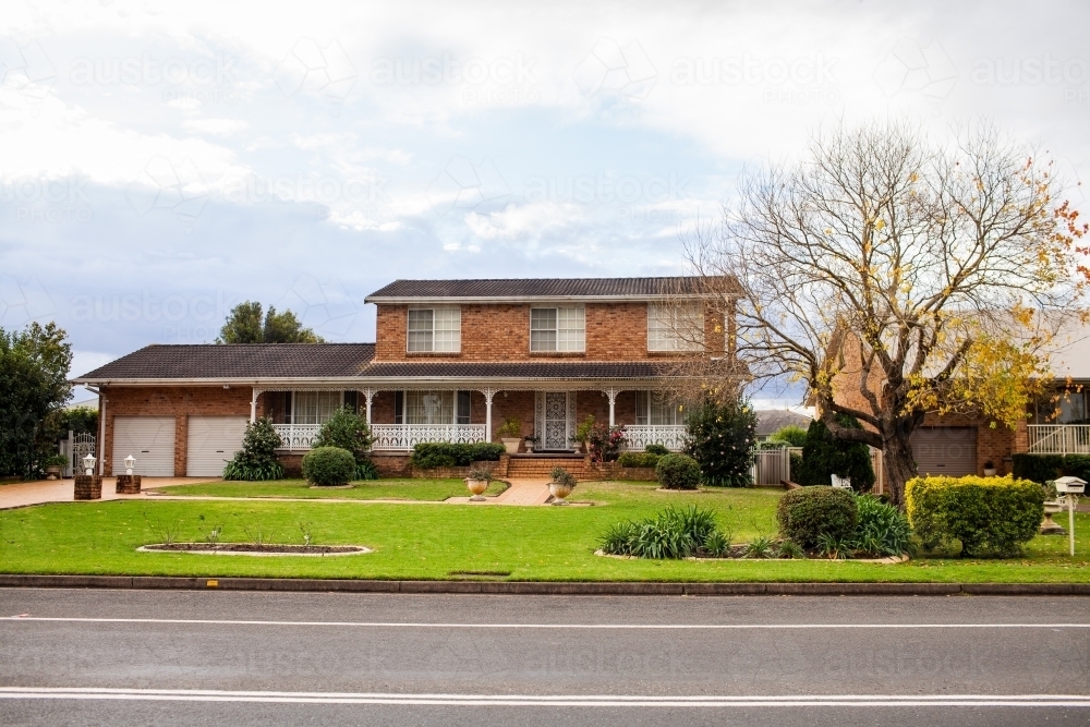 Image of house on street in autumn with neat garden and double garage ...