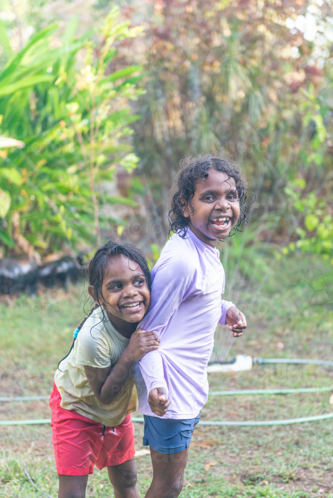 Image of Hugging aboriginal sisters having water play - Austockphoto