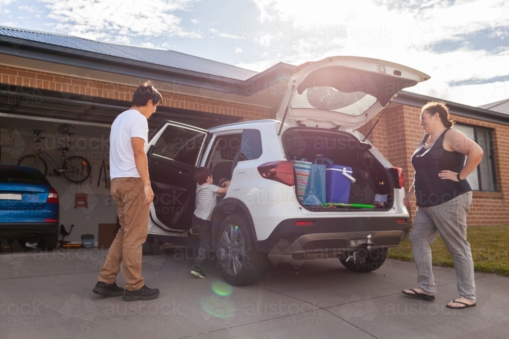 Image of Husband and wife packing family car before Saturday sports ...
