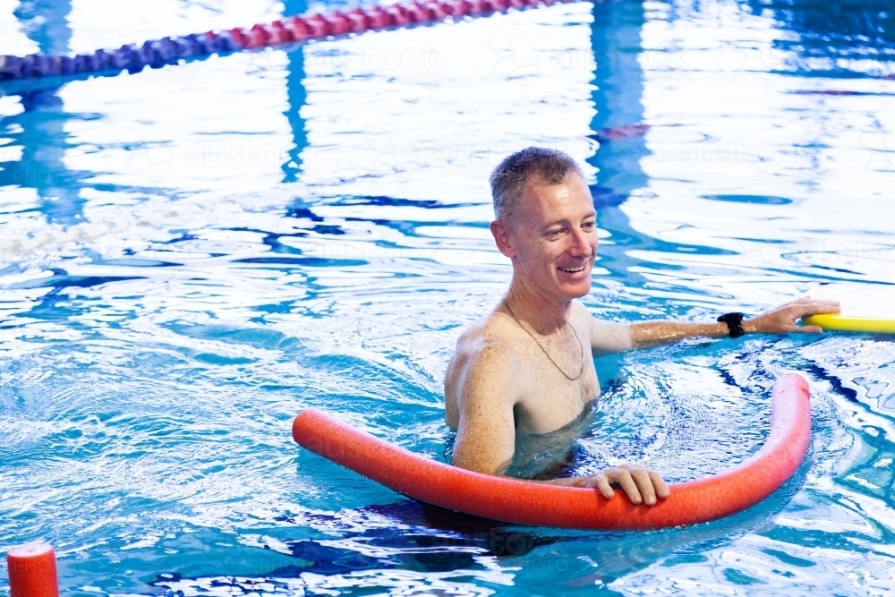 Image of Hydrotherapy physio instructor in pool with noodle - Austockphoto