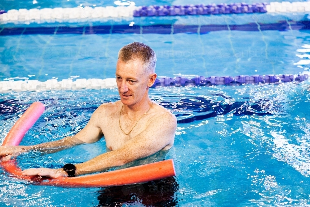 Image of Hydrotherapy physio instructor in pool with noodle - Austockphoto