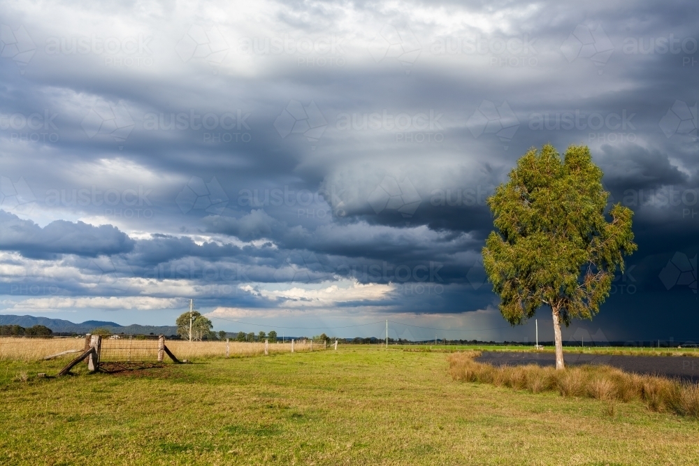 Image of Incoming dark stormy rain clouds over sunlit rural farm ...