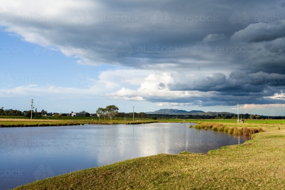 Image of Incoming rain clouds over dam on farm in australian ...