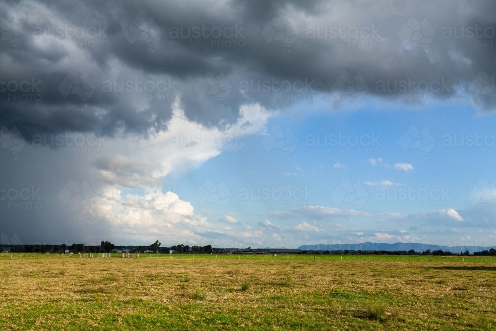 Image of Incoming storm with distant rain on farmland - Austockphoto