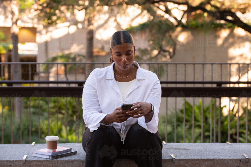 Image of indian australian woman using phone in an outdoor setting ...