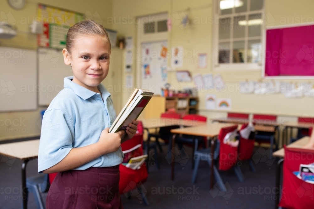 Image of Indigenous primary school female student holding books in a ...