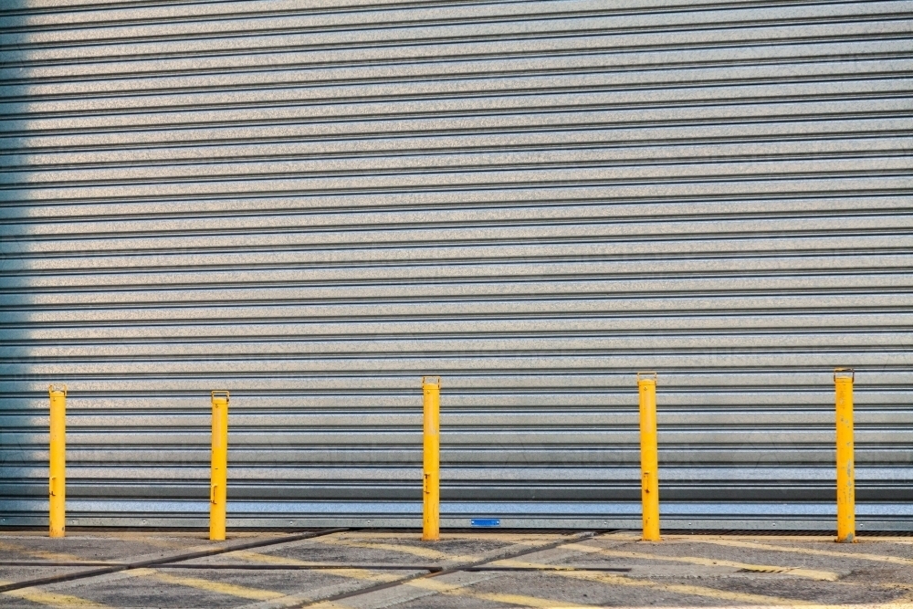 Image of Industrial metal roller door with yellow posts blocking entry ...