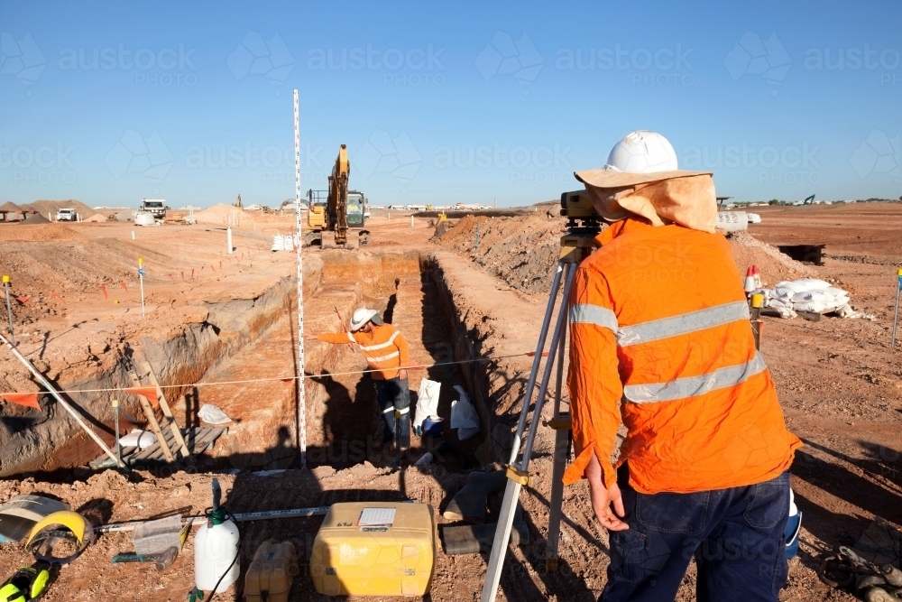 Image of Industrial workers surveying a large building site - Austockphoto