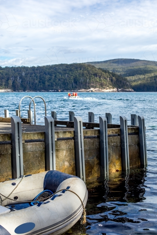 Image of Inflatable dinghy beside a jetty - Austockphoto