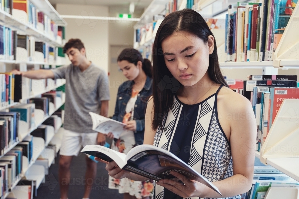 Image of International student reading book in university library ...
