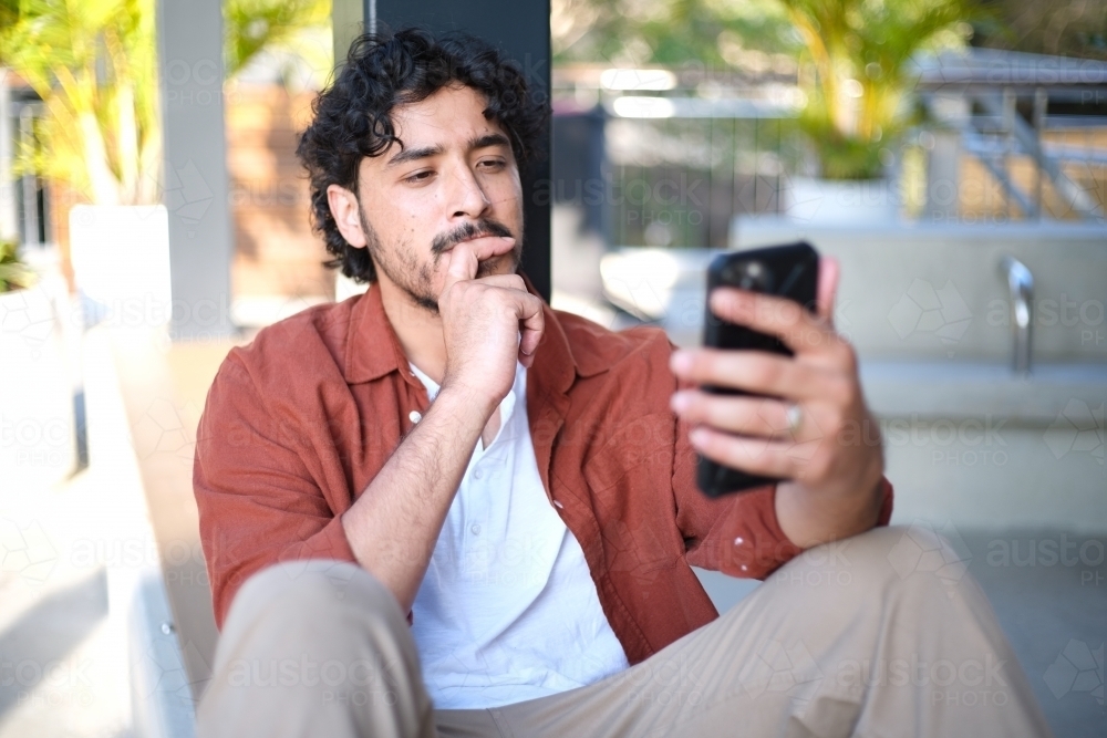 Image of Intrigued man on mobile phone outside - Austockphoto