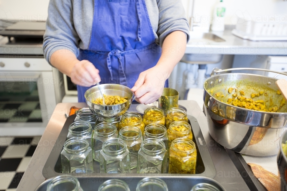 Image of jars of pickle being filled in small commercial kitchen ...