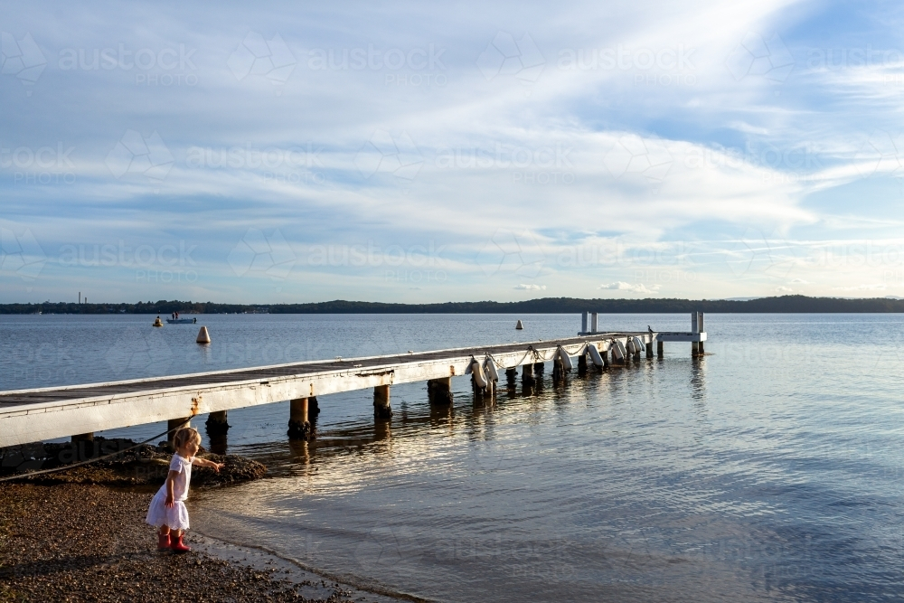 Image of jetty on shoreline of coastal lake with child throwing stones ...
