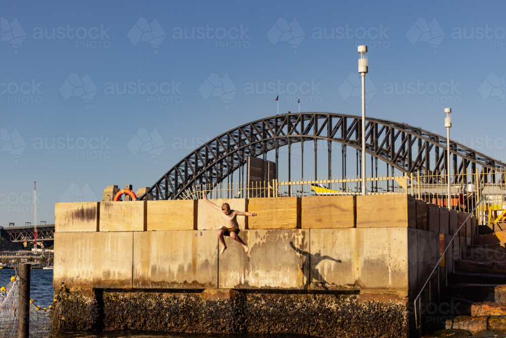 Image of Kid jumping from ledge into water with Sydney Harbour Bridge ...