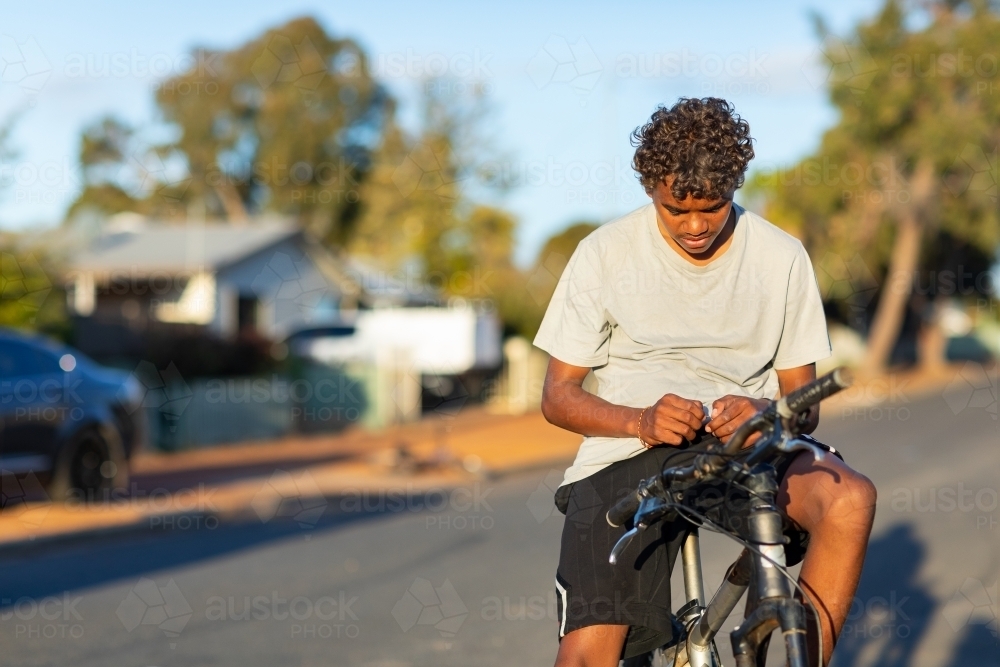 Image of kid resting on bike looking down at hands - Austockphoto
