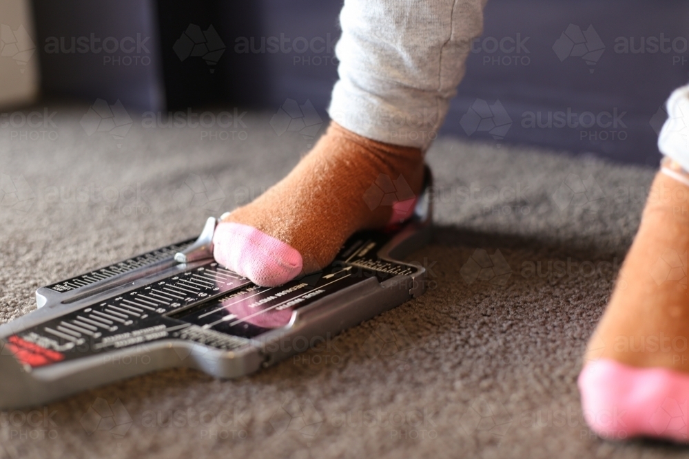 Image of kid's foot wearing brown and pink socks on a foot measuring ...