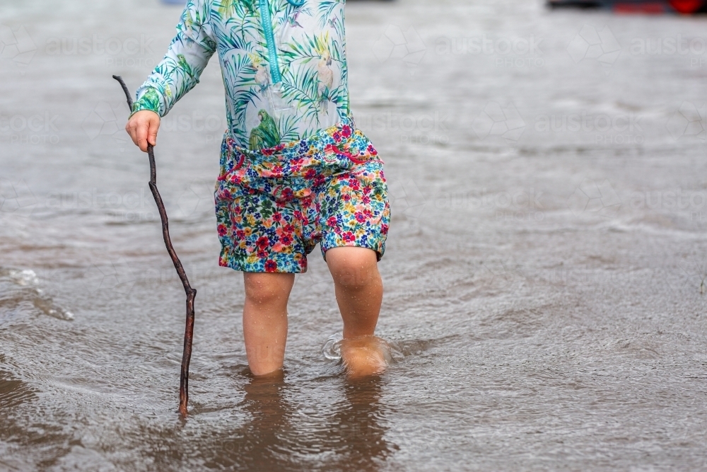 Image of Kid with stick playing in lake in summertime - Austockphoto